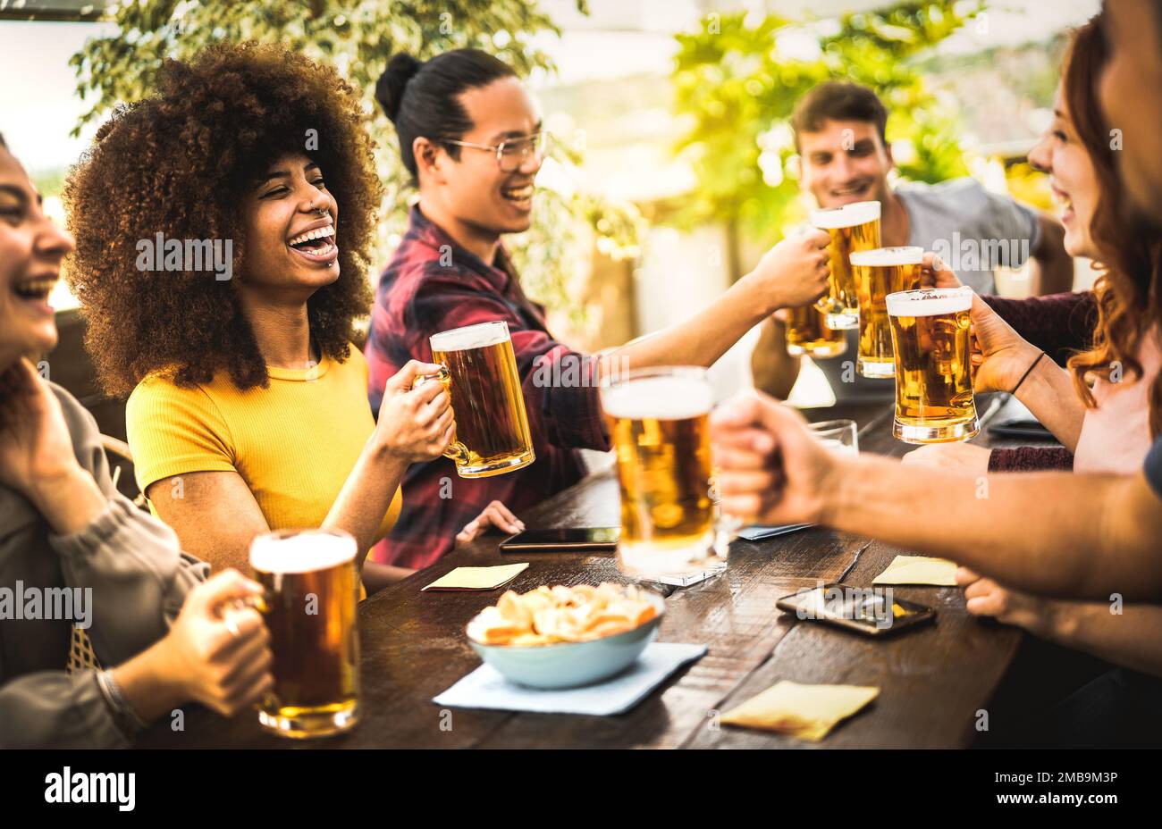 Multicultural people drinking and toasting beer pint at brewery bar ...