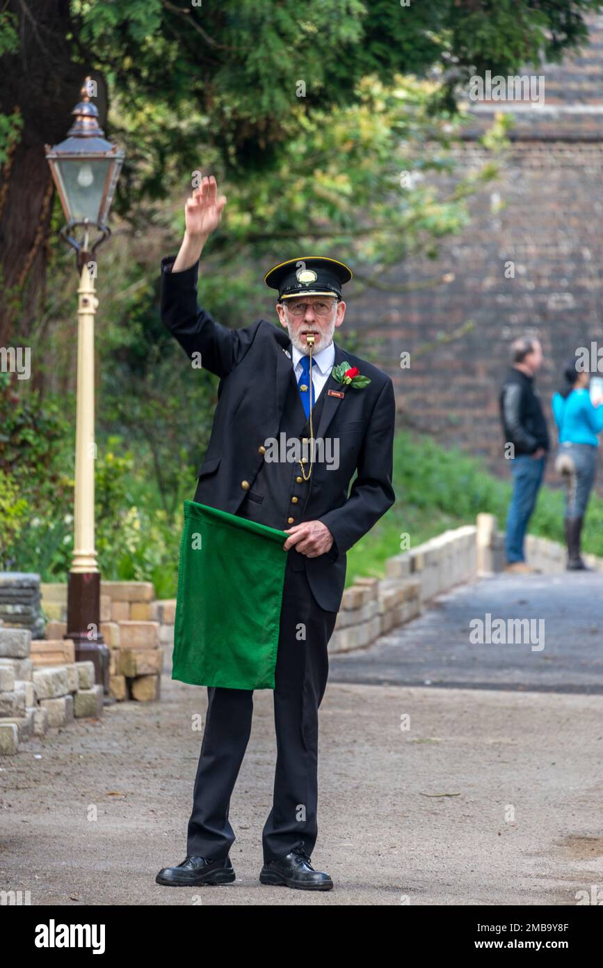A steam train guard waves his green flag to the engine driver as a ...