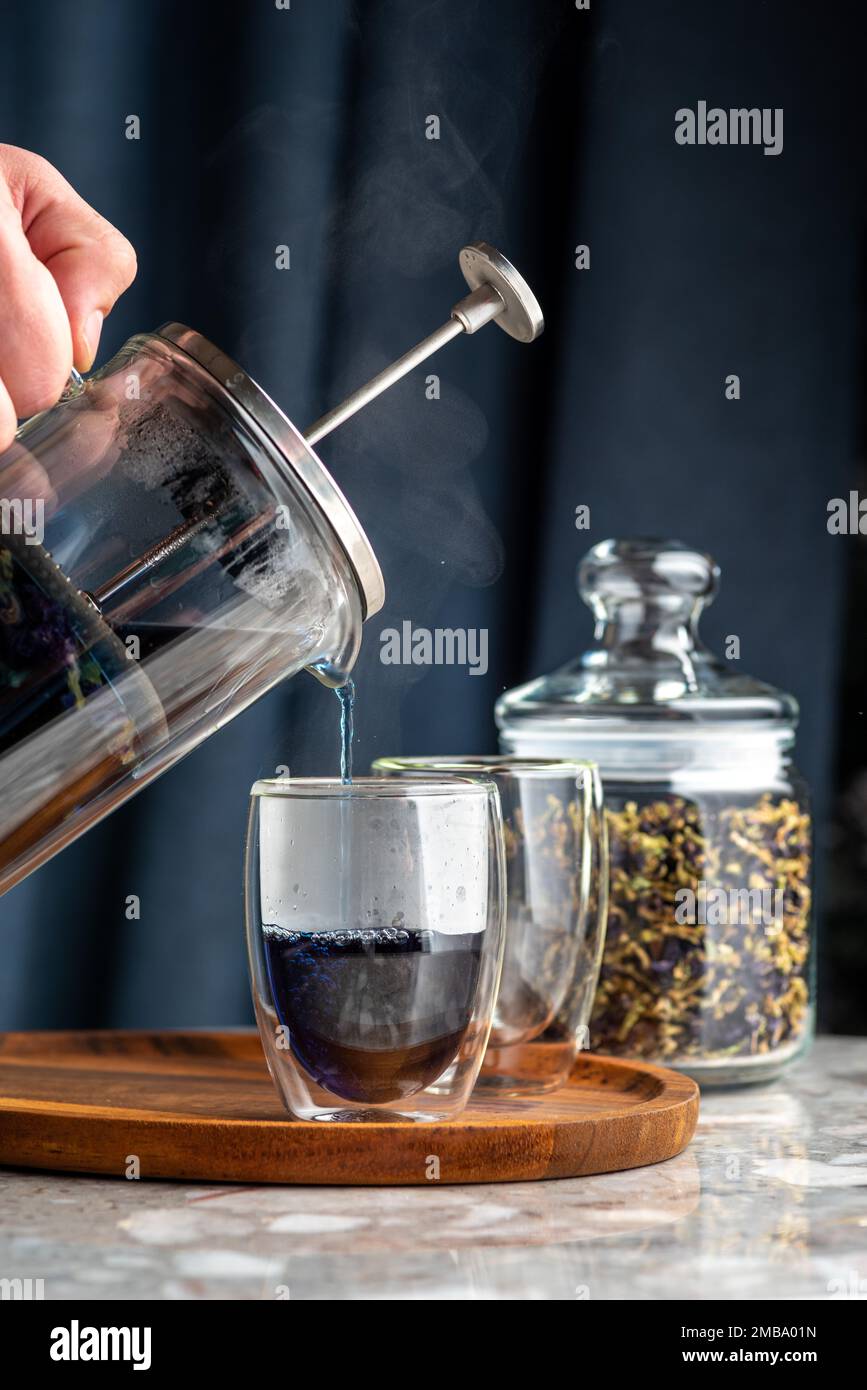 Thai anchan blue tea is poured from the kettle into a transparent glass ...