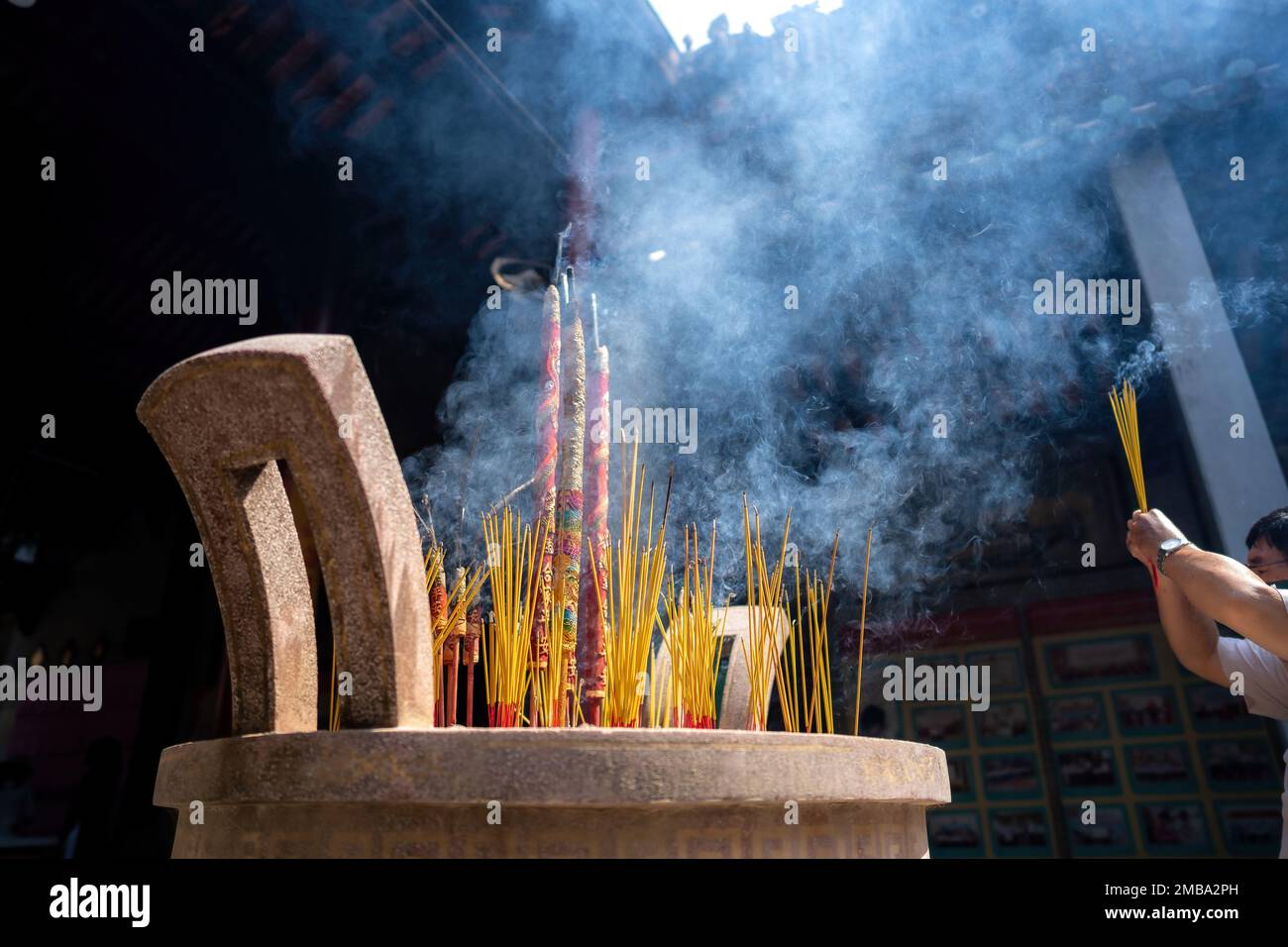close-up of a hand holding incense. The background is an unspecified ...