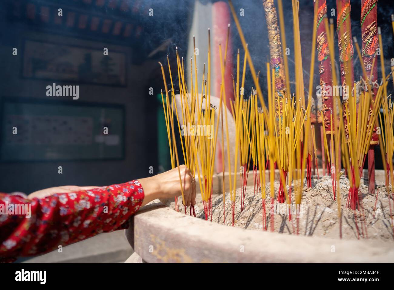 close-up of a hand holding incense. The background is an unspecified ...