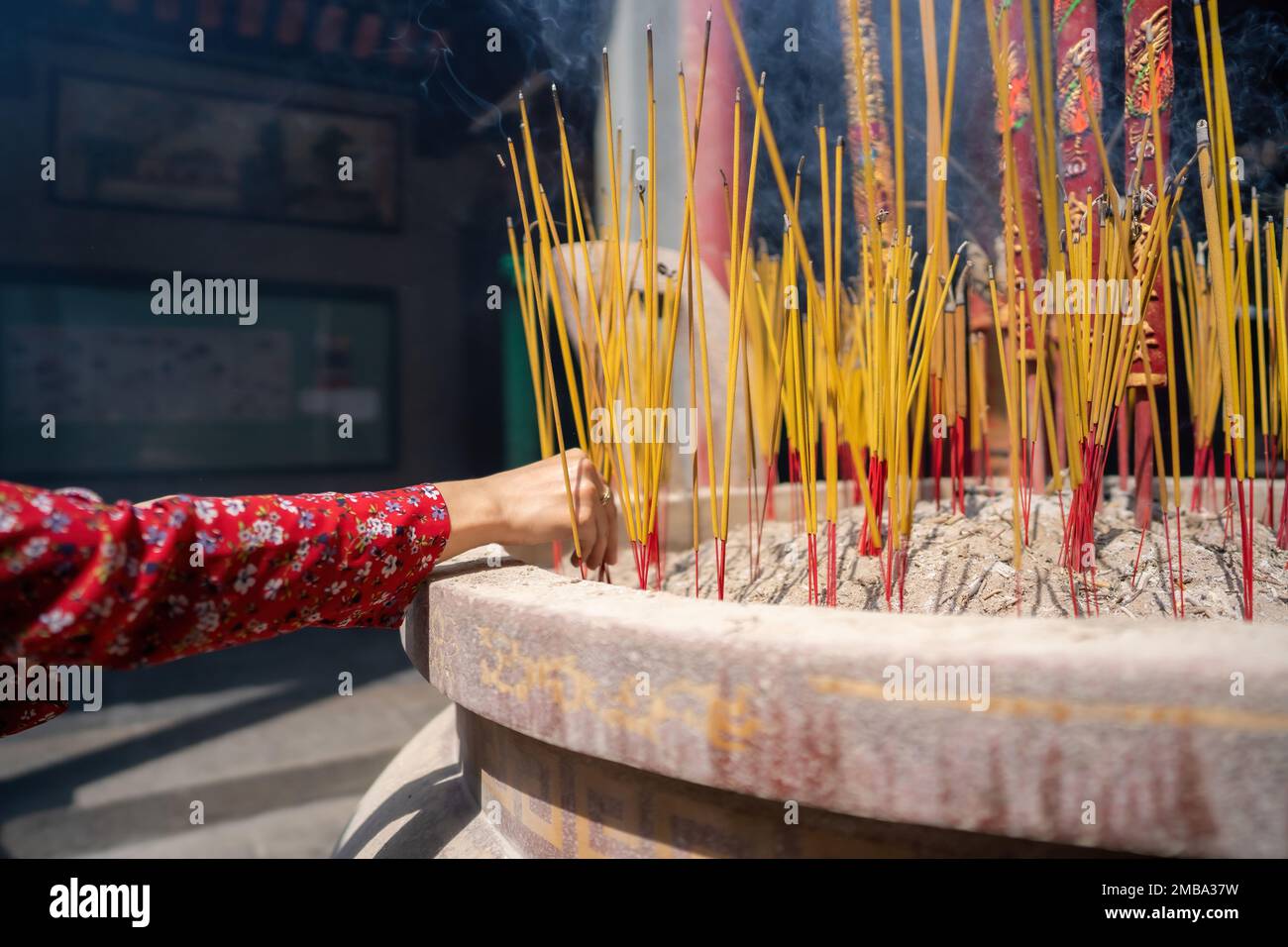 close-up of a hand holding incense. The background is an unspecified ...
