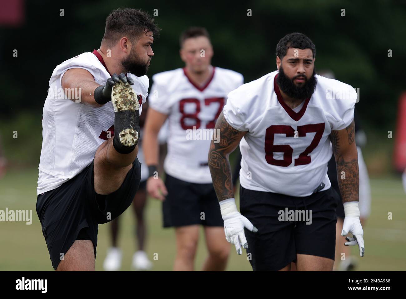 Washington Commanders offensive lineman Samuel Cosmi, left, stretches ...