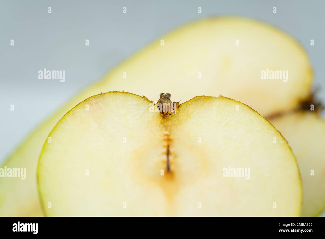 Pear fruit split in half on a white background in a very close ...