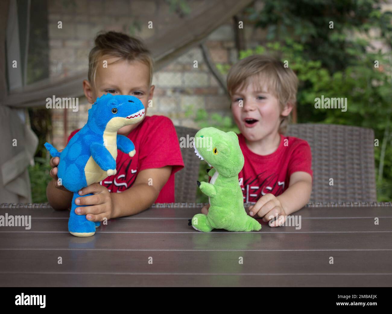 Toddler boys play at the table with plush dinosaurs in role-playing ...