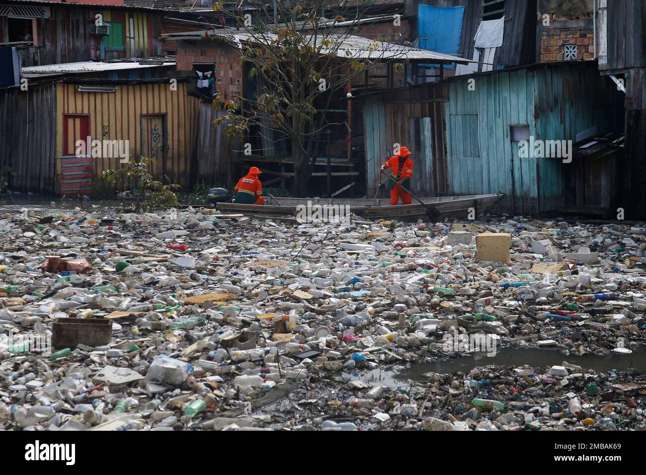 City workers remove garbage floating on the Negro River, which has a ...