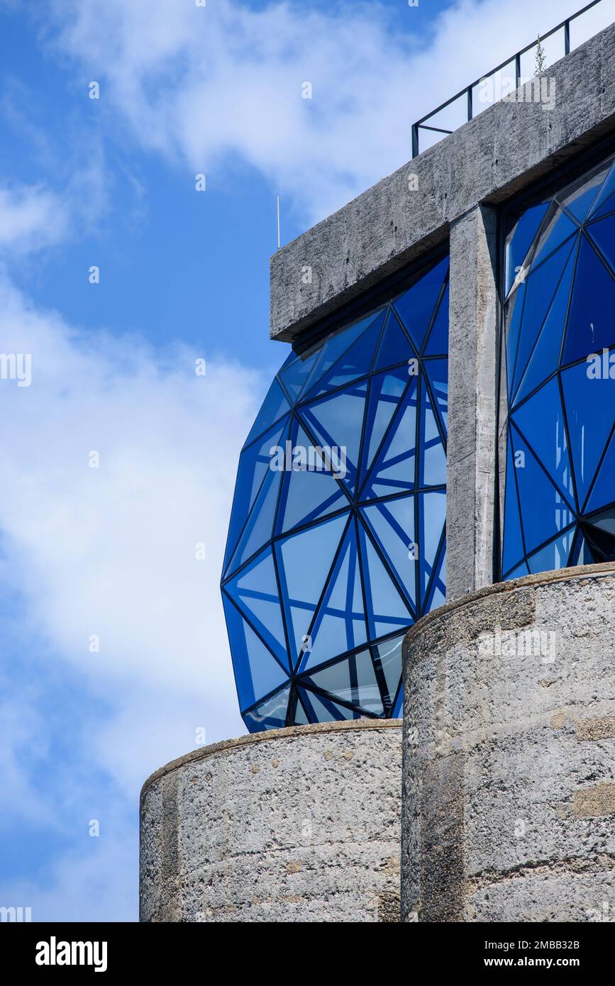 A vertical shot of blue glass paned window bulging out from concrete ...