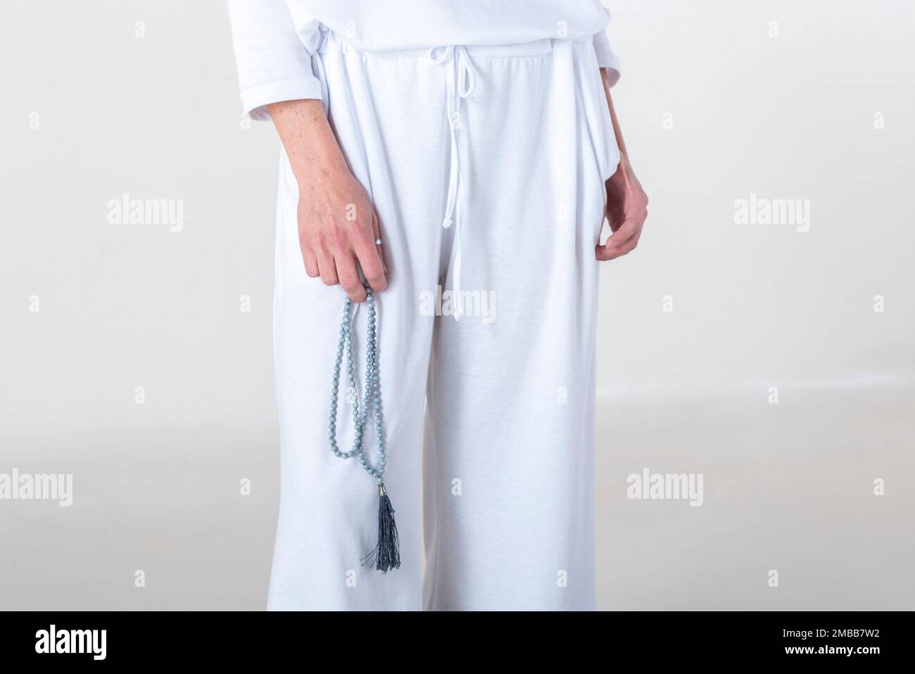 Close up of a hand holding a japa mala over white background. Studio ...