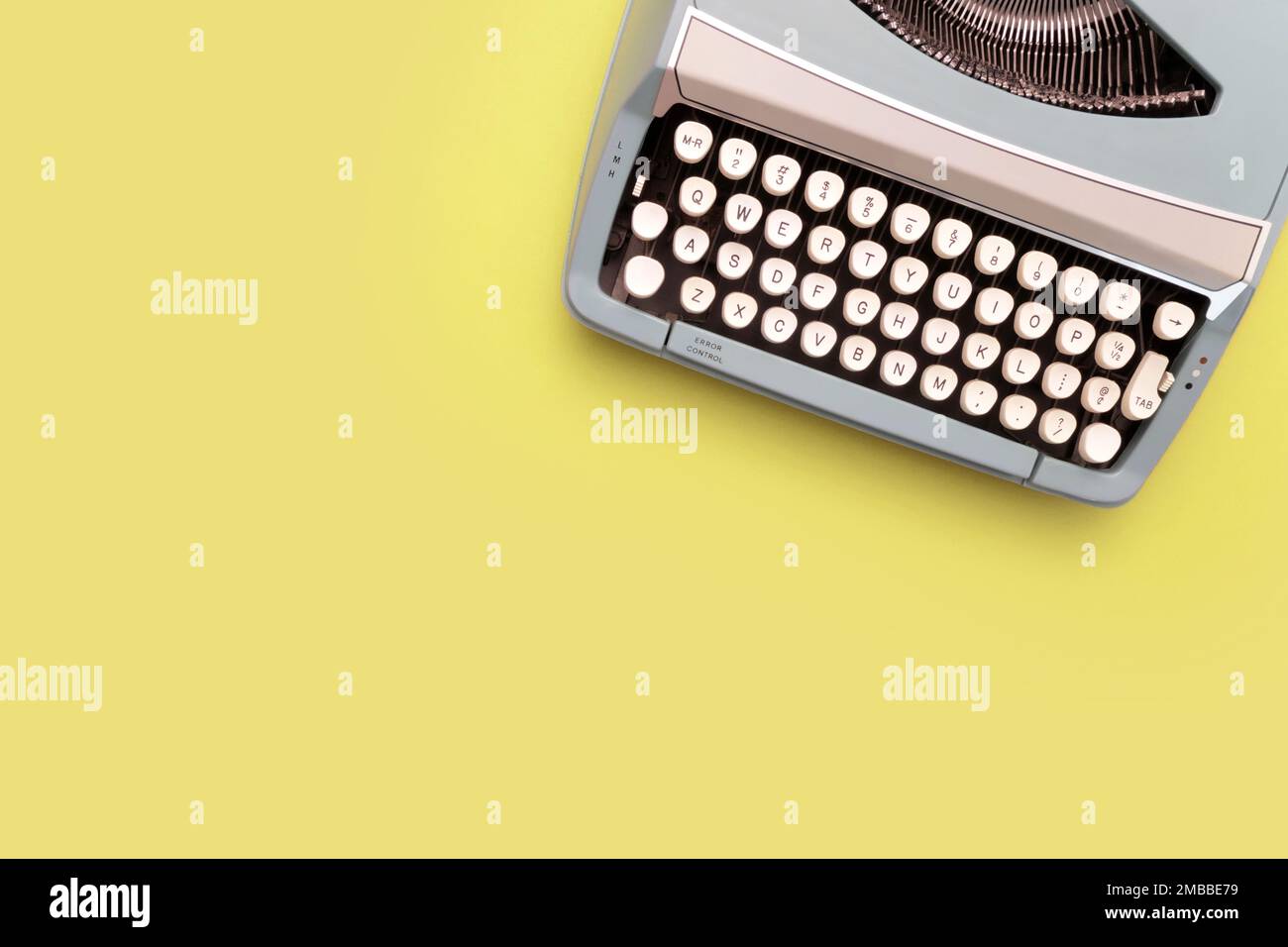 Overhead top view of a vintage aqua blue typewriter against a yellow ...