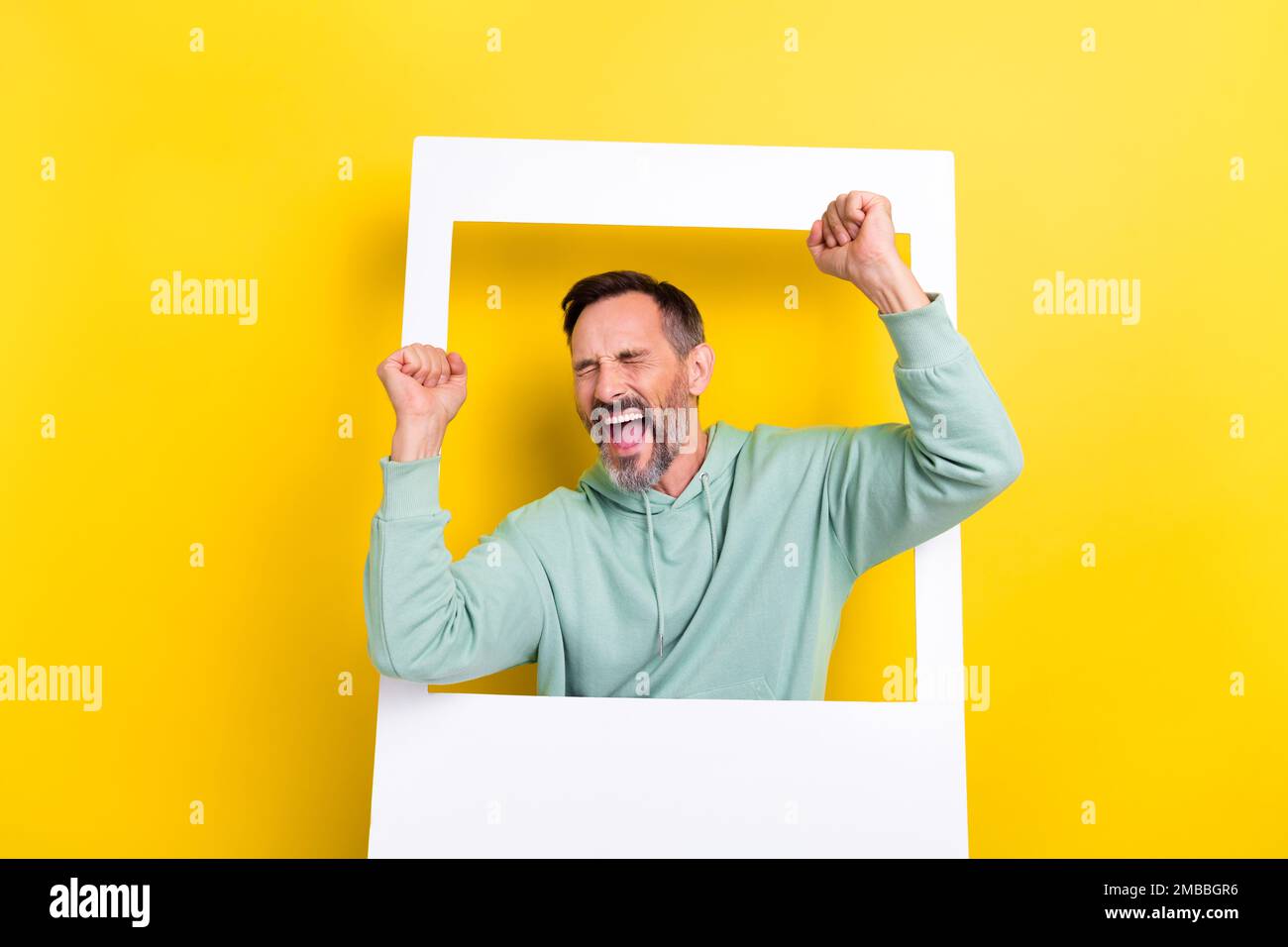 Portrait of ecstatic overjoyed man dressed green hoodie in white frame ...