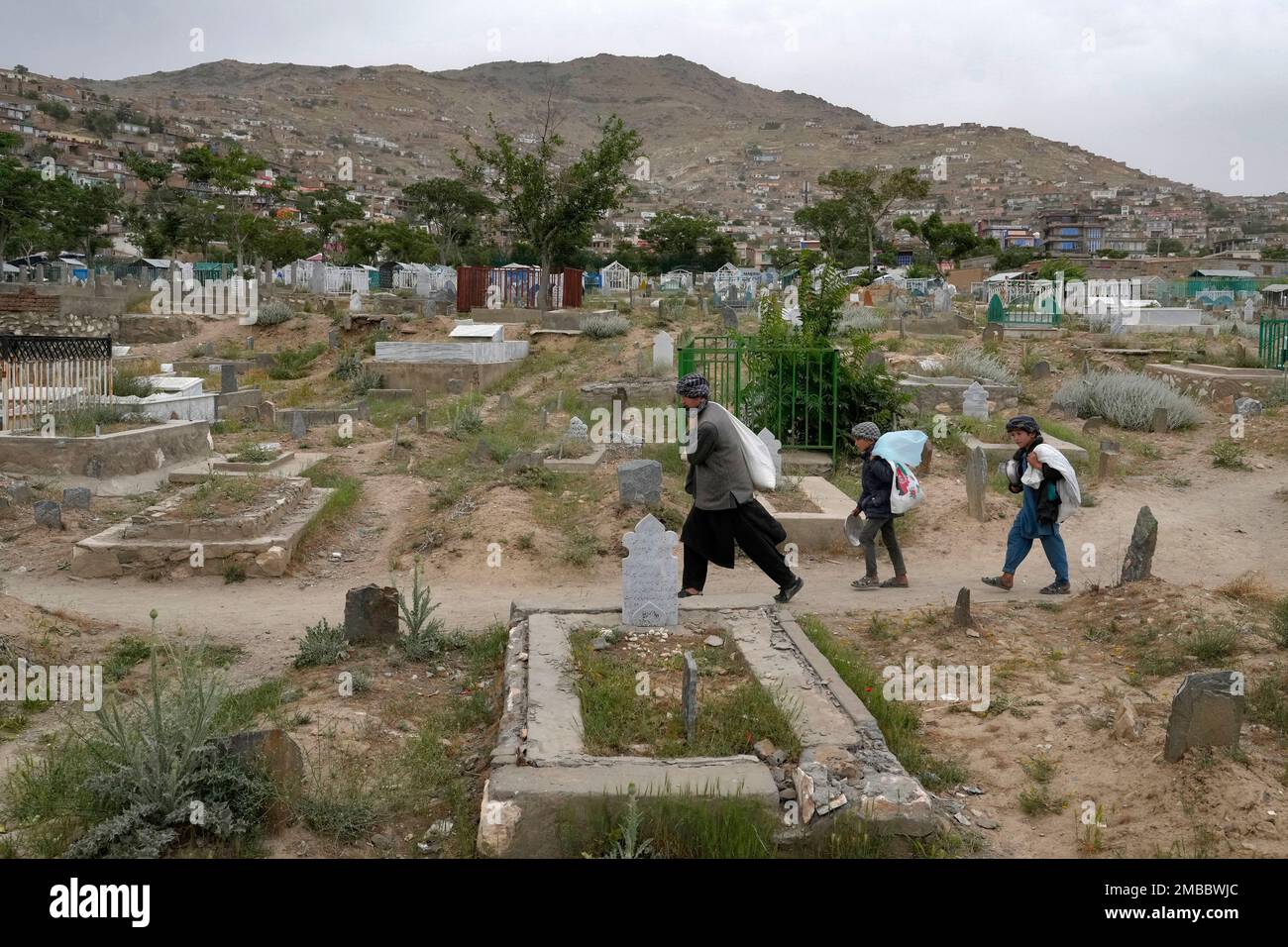 An Afghan man goes home with his sons through the cemetery in Kabul ...