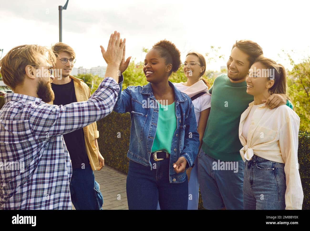 Group of happy young people give each other high five during meeting on ...