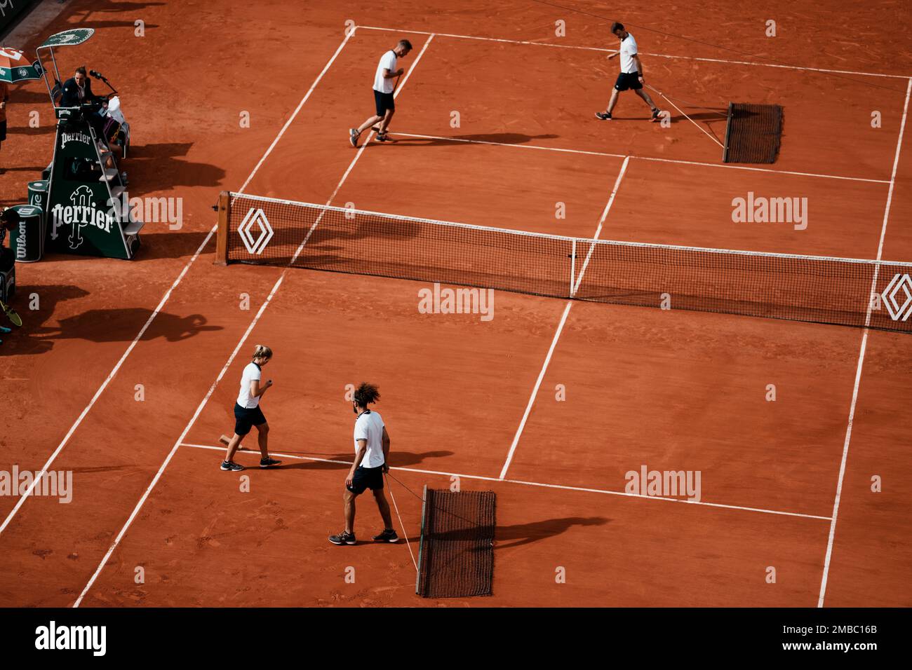 Stadium workers sweep the clay court during fourth round matches at the ...