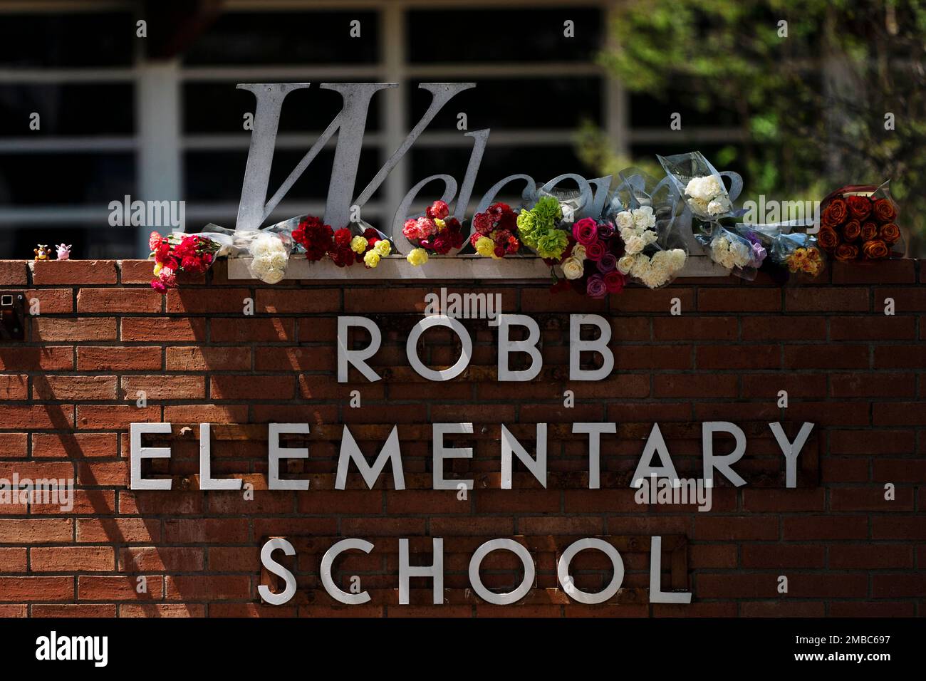 FILE - Flowers are placed around a welcome sign outside Robb Elementary ...