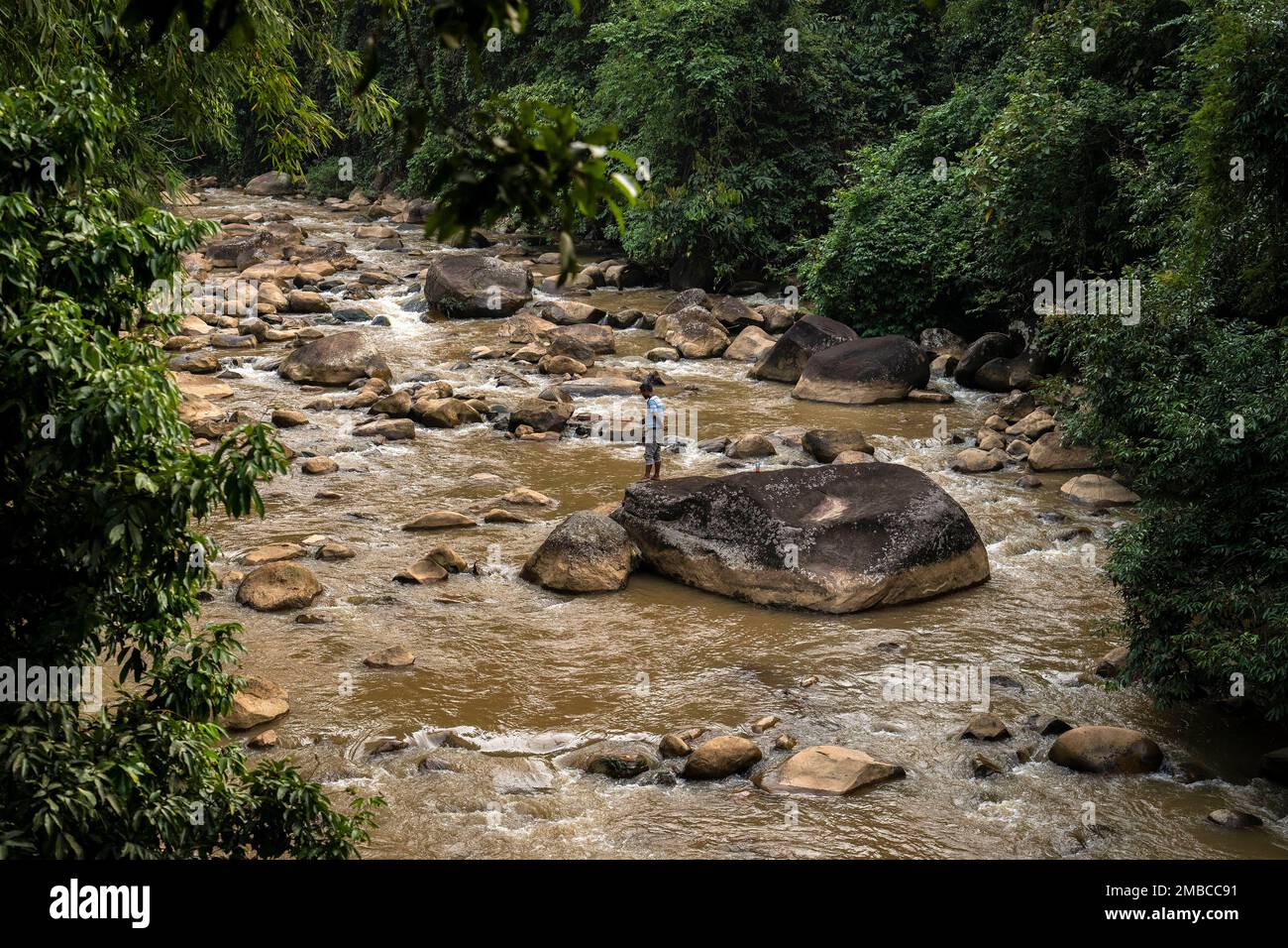 A tribal Khasi man catches fish in a river along the Assam-Meghalaya ...
