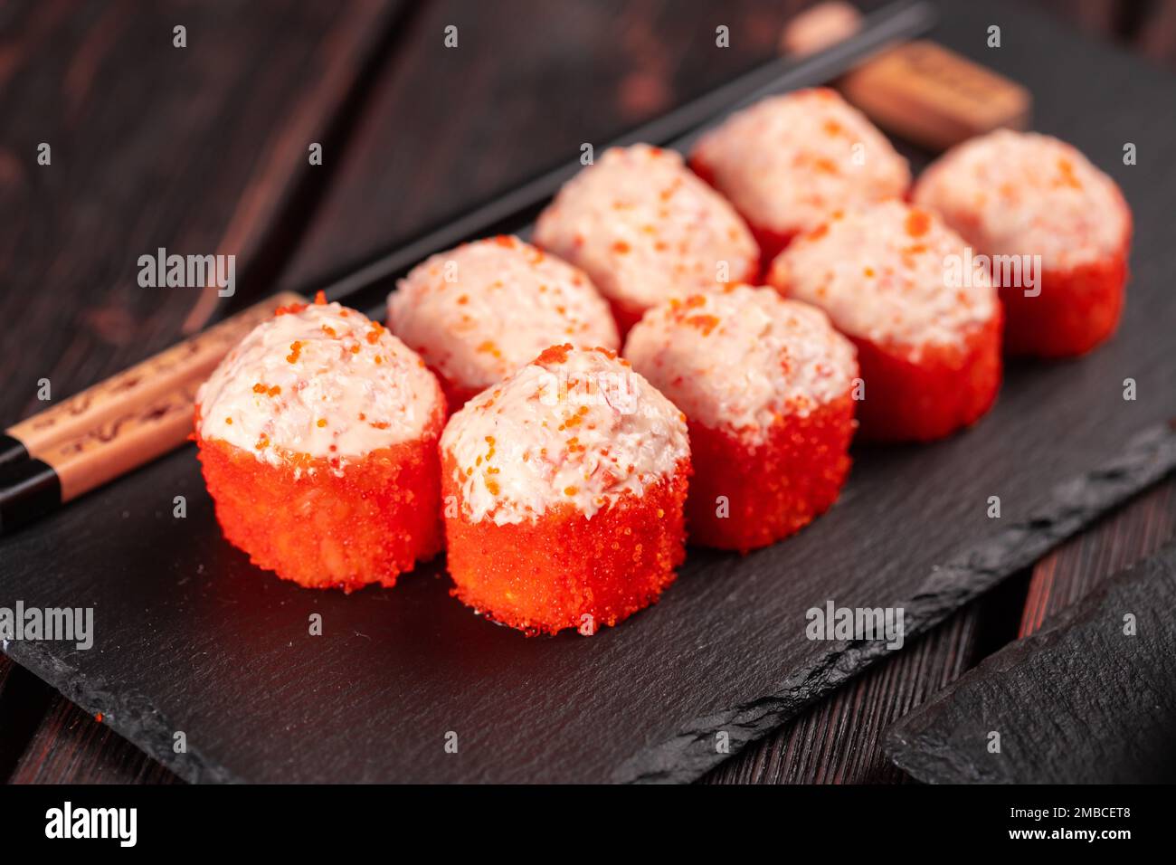 Sushi roll with mayonnaise sauce and red tobiko caviar served on black ...
