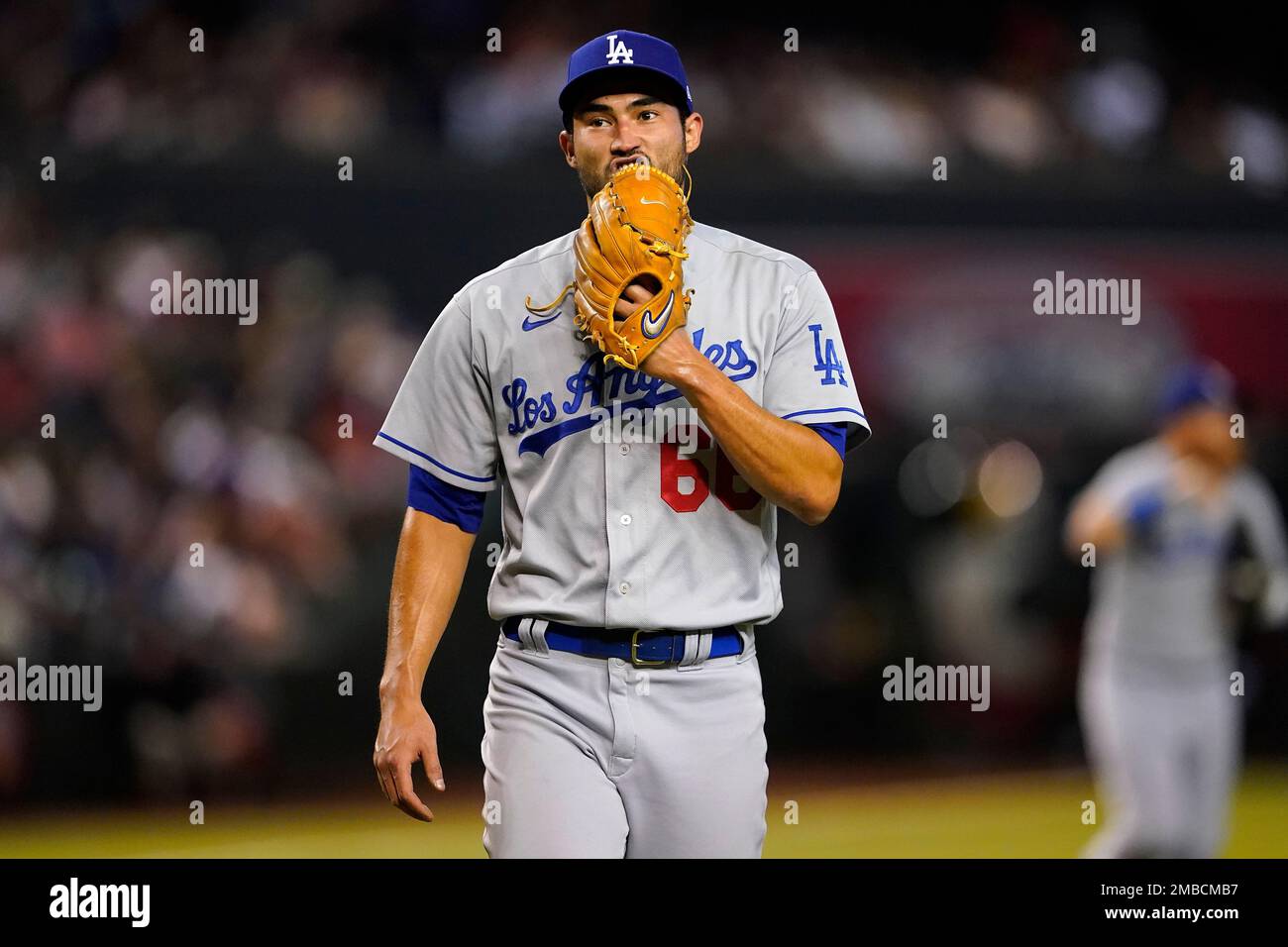 Los Angeles Dodgers pitcher Mitch White bites on his glove as he walks ...