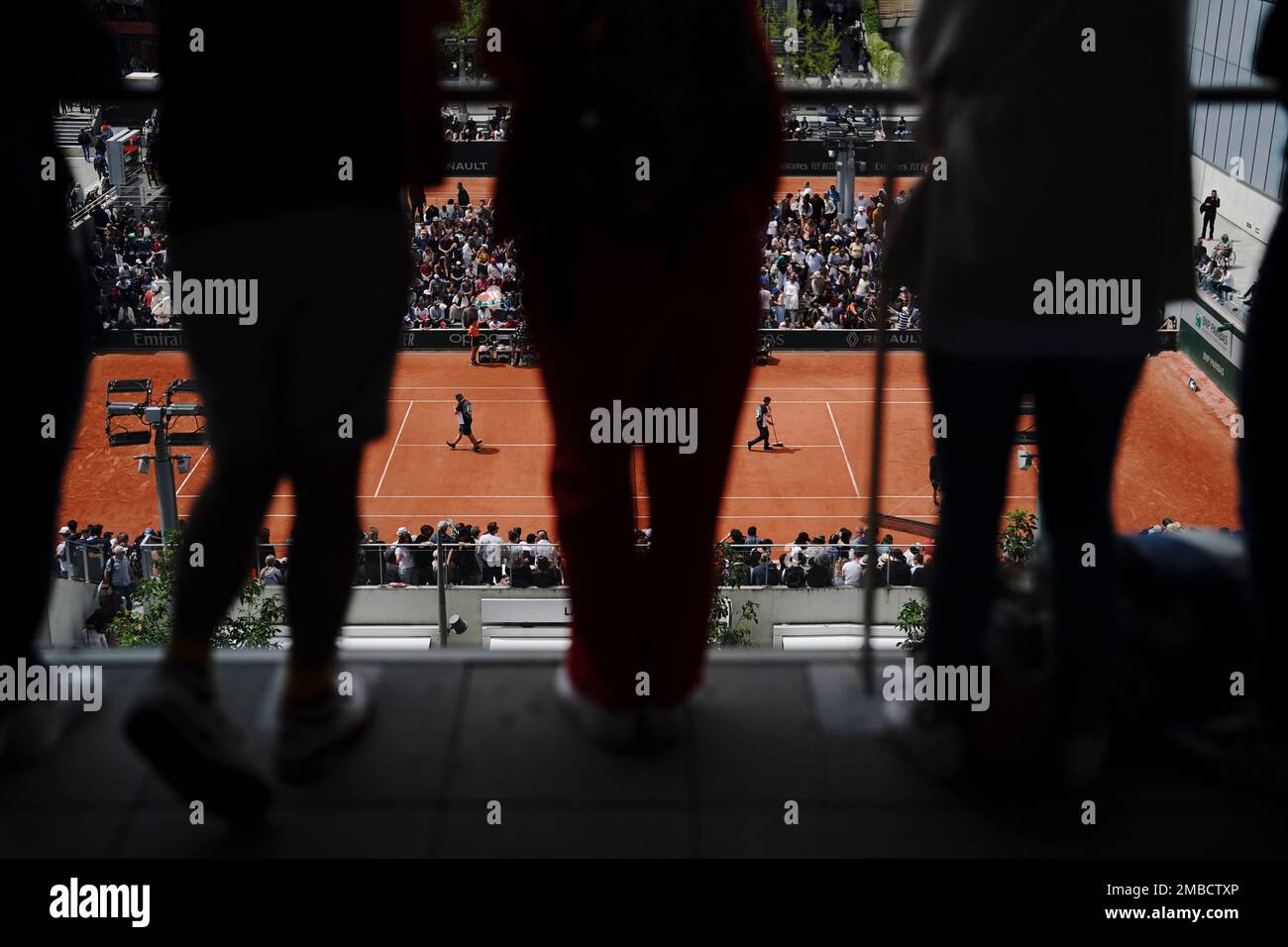 Spectators watch as stadium workers sweep the lines of the court during ...