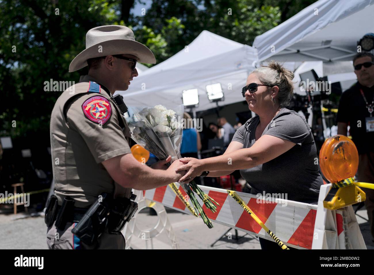 Sheena Rodriguez, 38, right, hands a state trooper a bouquet of flowers ...