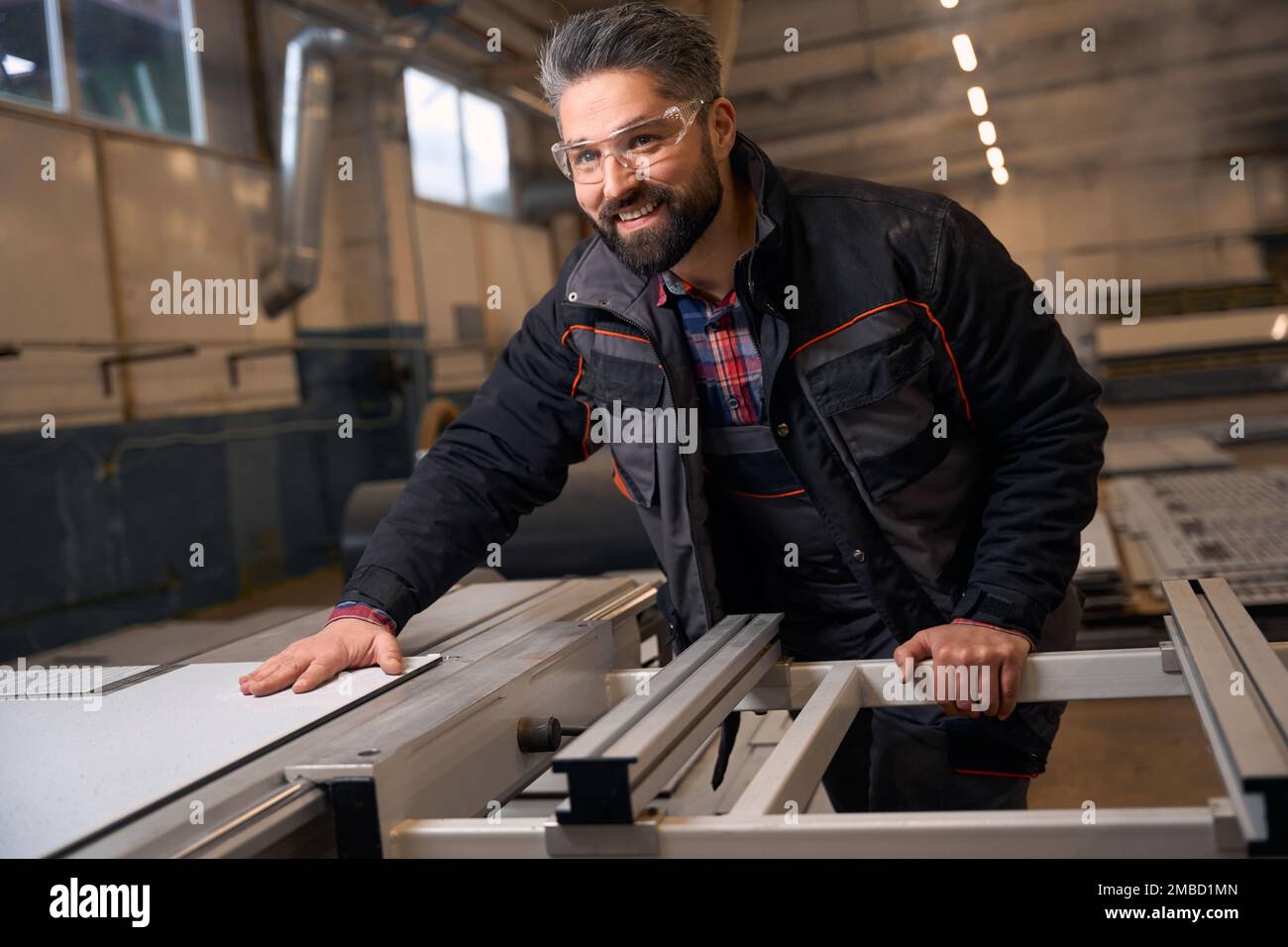 Handsome worker cutting wood in the workhouse Stock Photo - Alamy
