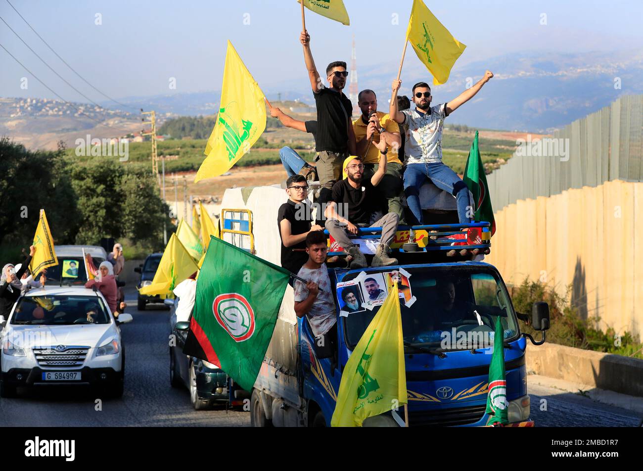 Hezbollah supporters wave Hezbollah flags, as they pass by their cars ...
