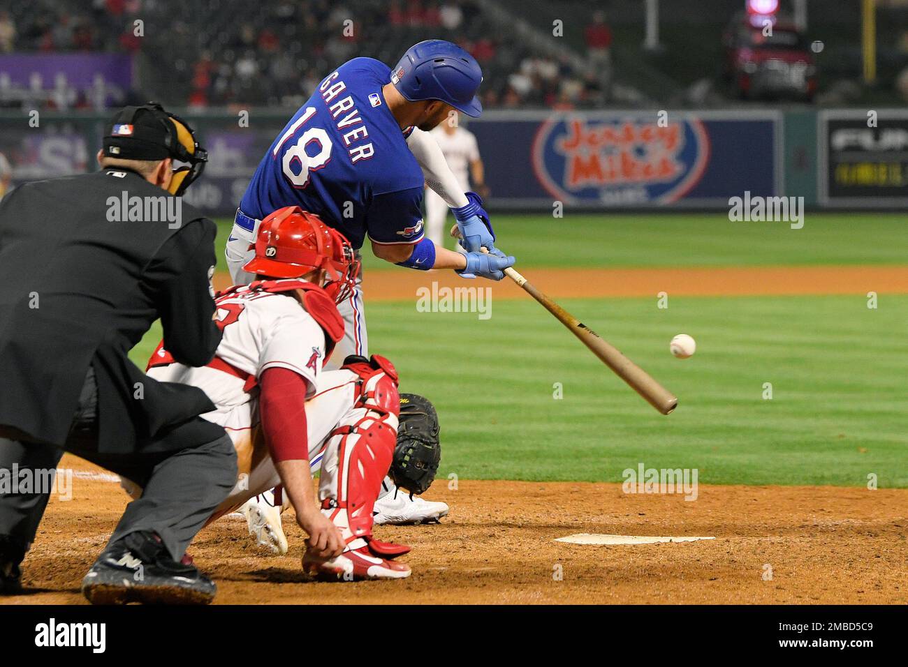 Texas Rangers' Mitch Garver, right, hits a solo home run as Los Angeles Angels catcher Max ...