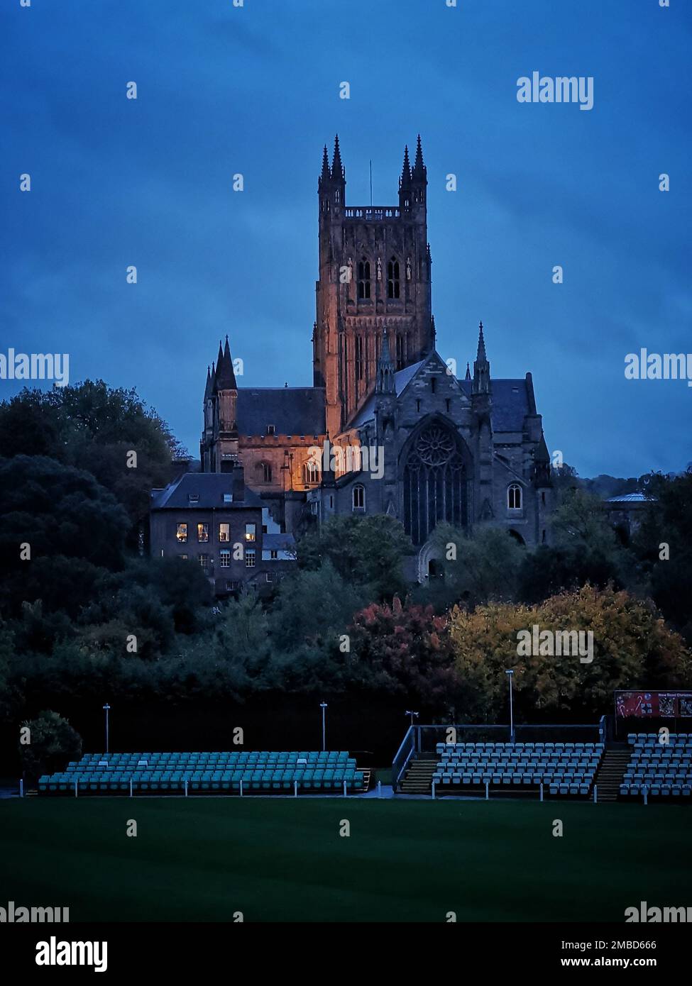 A vertical shot of Worcester Cathedral with fall trees in front of it ...