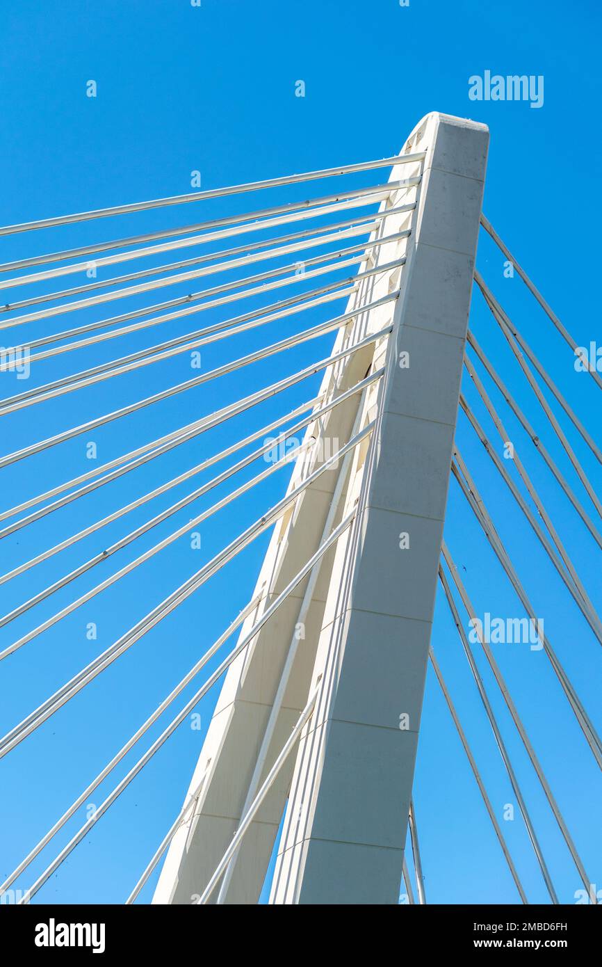 a side on image of a white concrete bridge pillar and cables against ...
