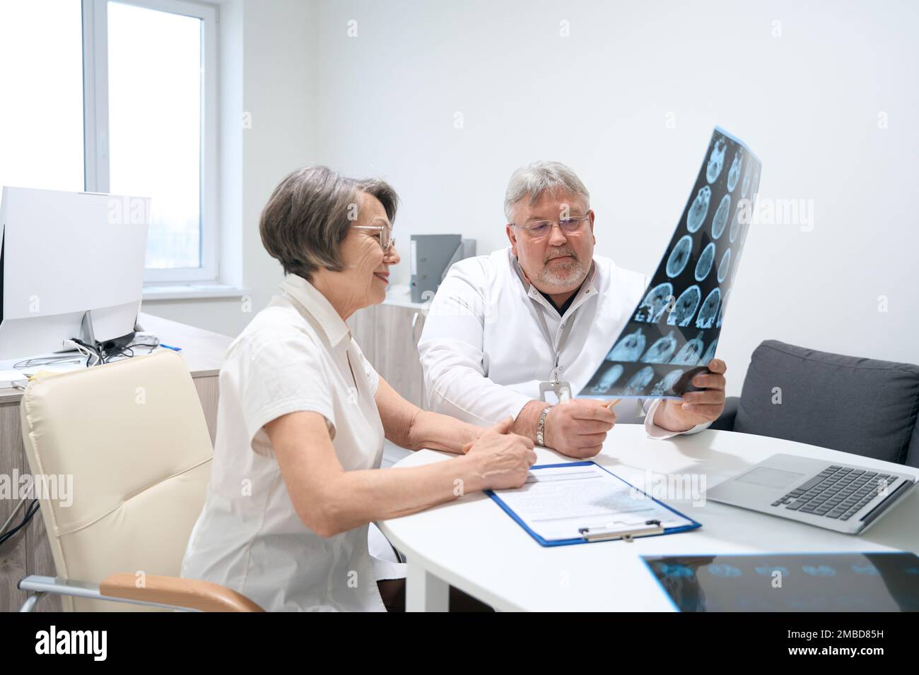 Elderly doctor and patient are studying MRI scans Stock Photo - Alamy