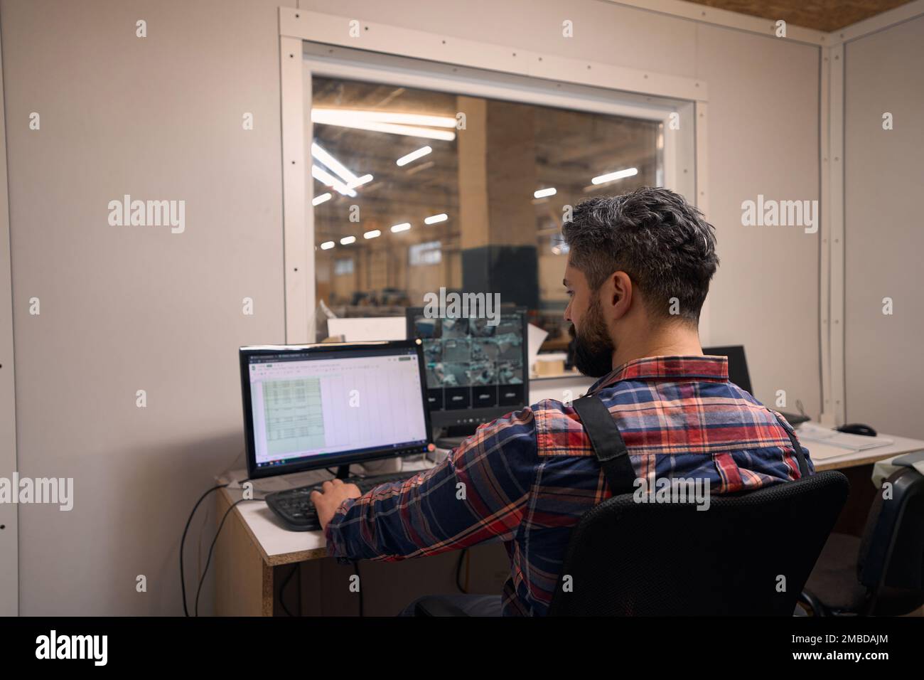 Security guard monitoring rooms of workshop through surveillance ...