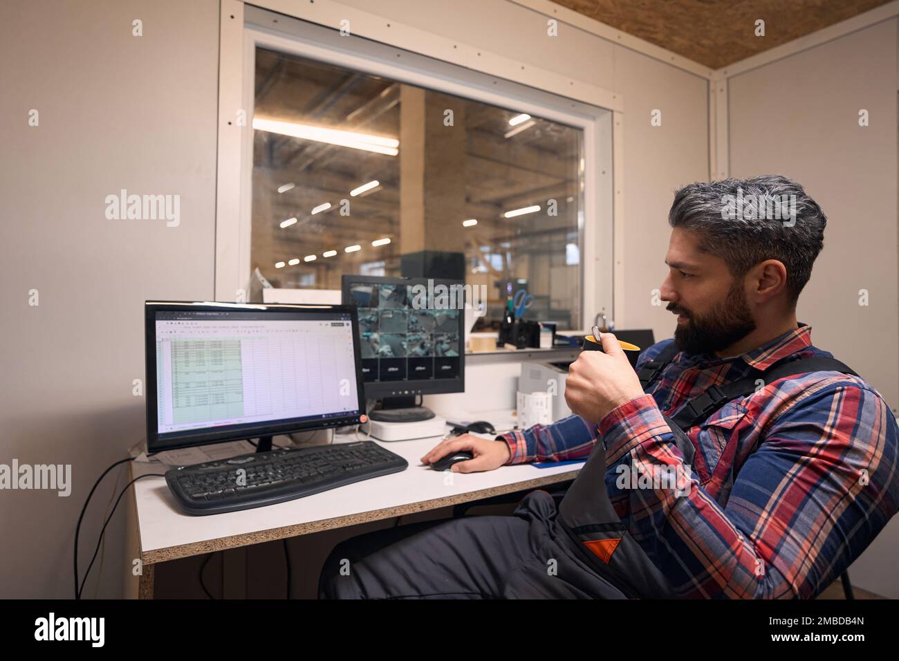 Male monitoring rooms of workshop through surveillance cameras Stock ...