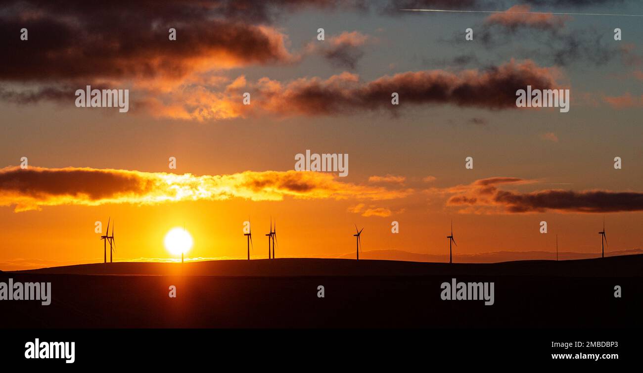A panoramic view of the orange-shaded sunset sky with wind turbines ...