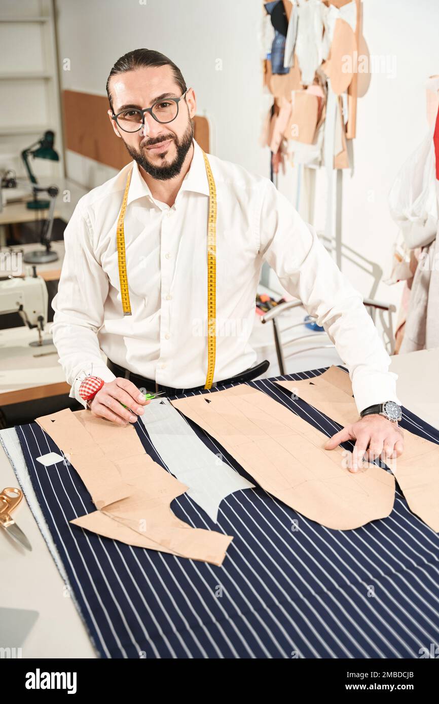 Confident clothier posing for camera before fabric cutting Stock Photo ...