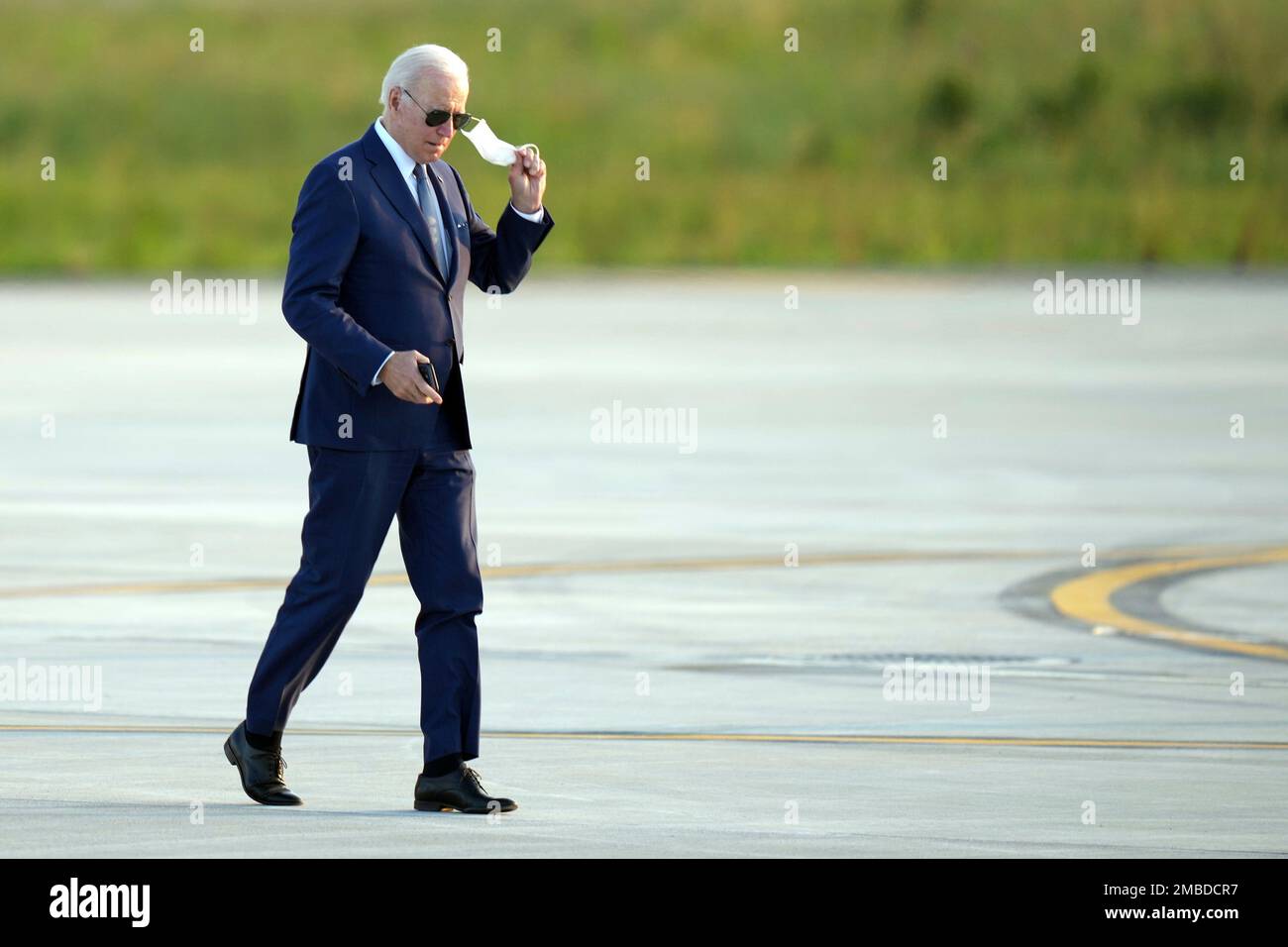 U.S. President Joe Biden takes off his protective mask as he walks to ...
