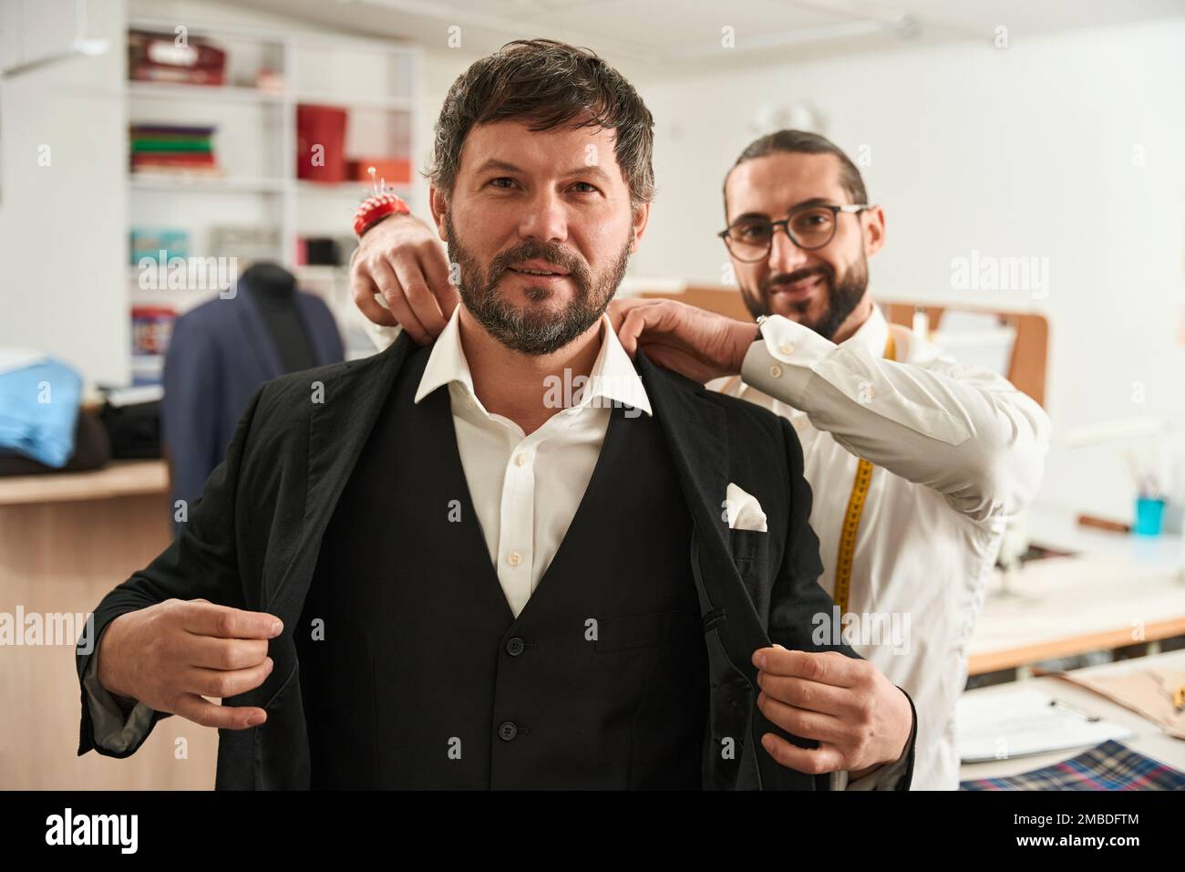 Man putting on suit during fitting session Stock Photo - Alamy