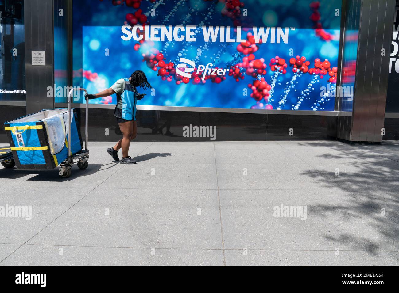A delivery person walks past a sign hanging outside Pfizer headquarters ...