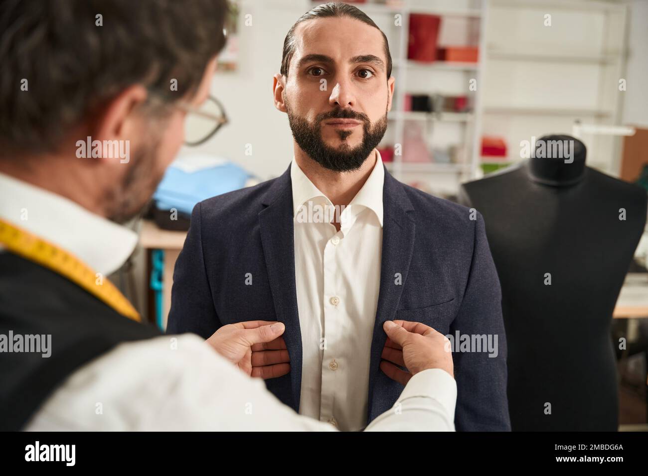 Fashion designer trying on garment on his client Stock Photo - Alamy