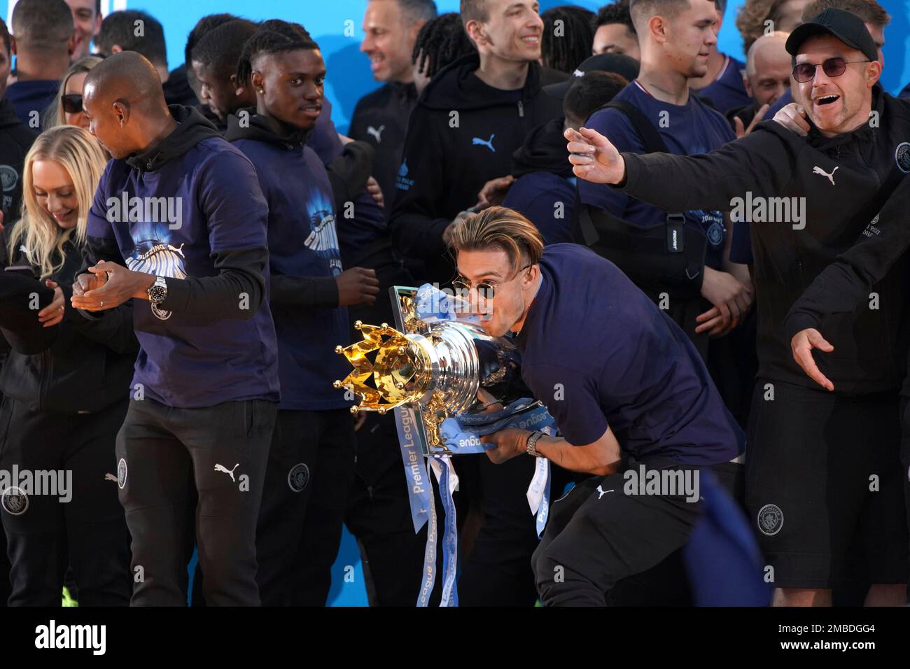 Manchester City's Jack Grealish holds the trophy on stage as fans watch ...