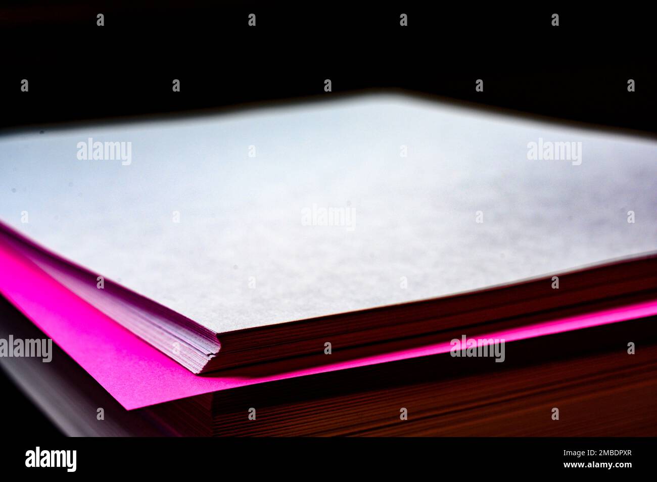 Selective focus on a single colored sheet in a stack of plain white ...