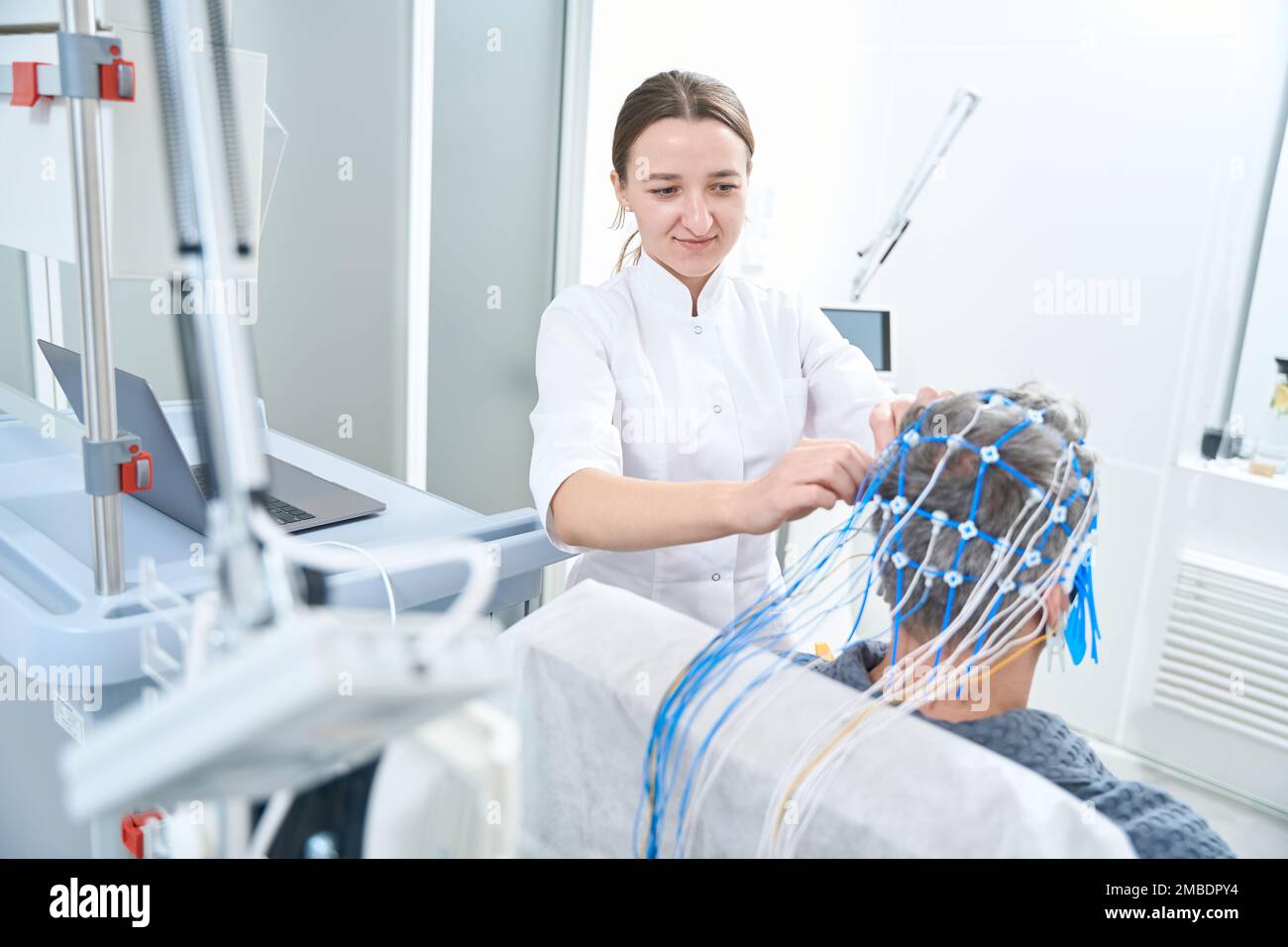 Woman diagnostician attaches sensors to the patient head Stock Photo ...