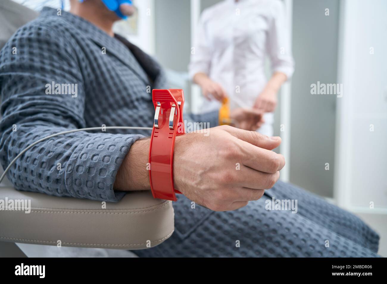 Man in hospital gown sits with sensors on his wrists Stock Photo - Alamy