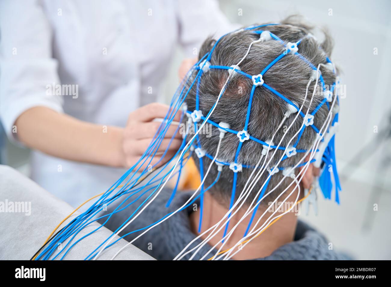 Patient in hospital gown sits with sensors on his head Stock Photo - Alamy