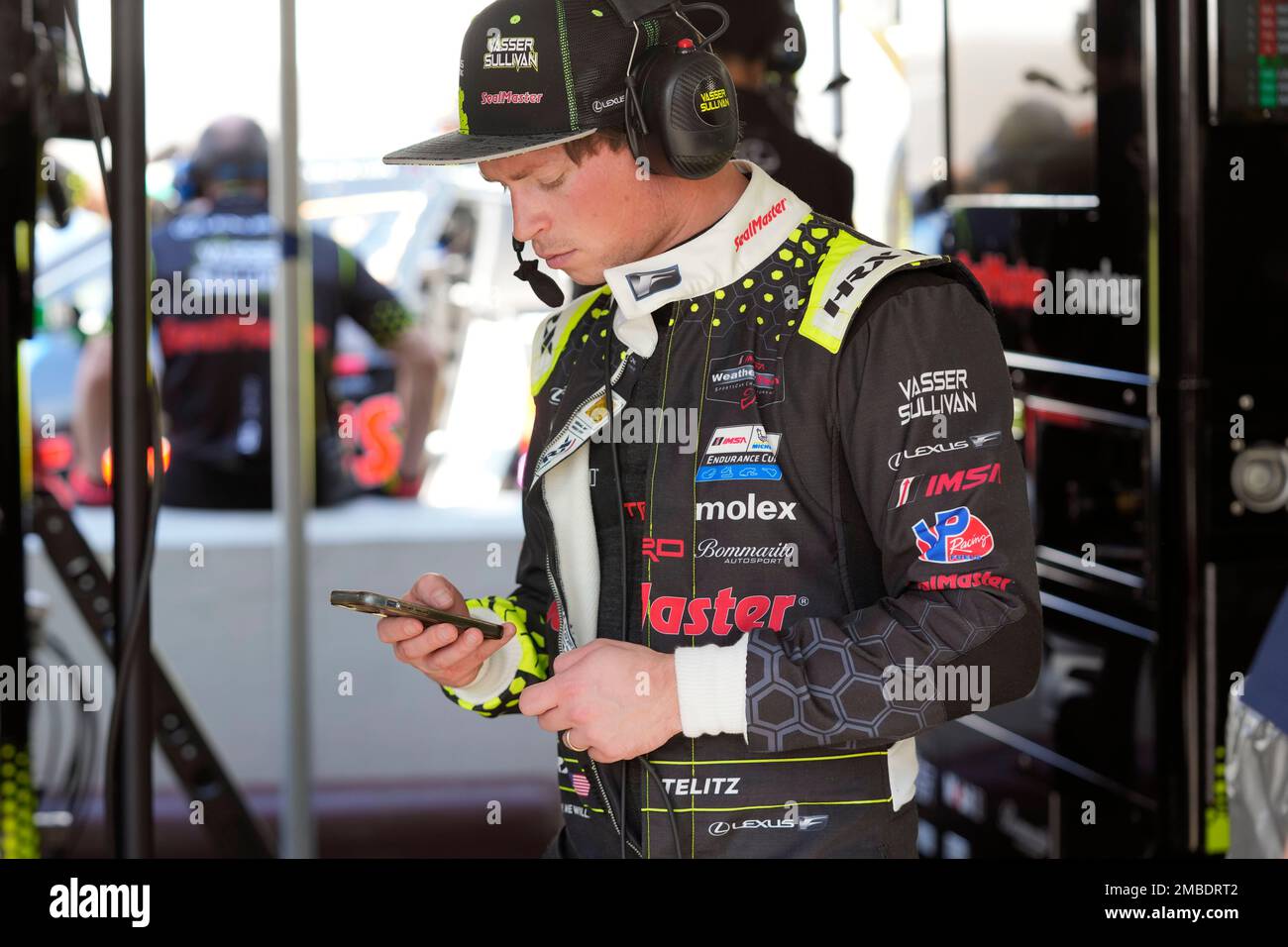 Aaron Telitz checks his cell phone in his pit stall during auto race ...