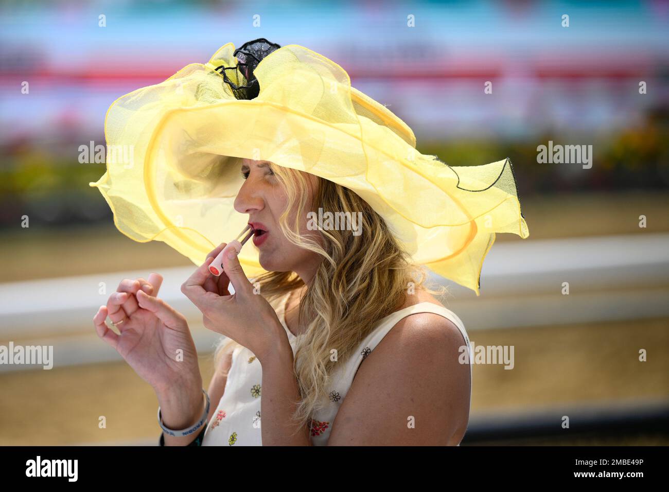 Kaitlyn Tauber, wearing a decorative hat, applies lipstick prior to the ...