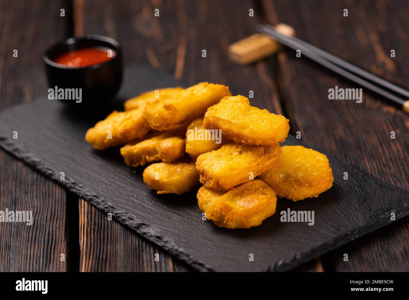 Fried chicken pieces on stone board with chopsticks - asian food close ...