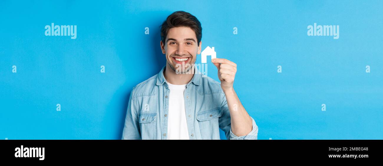 Real estate concept. Young handsome man smiling, showing small paper ...