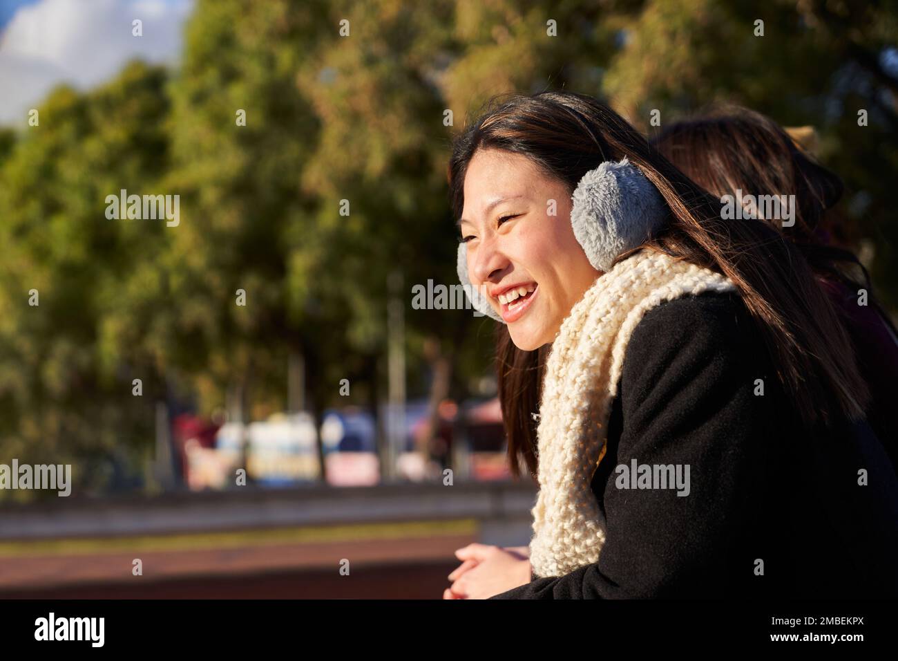 Young woman leaning on a bridge looking away, enjoying the view and ...