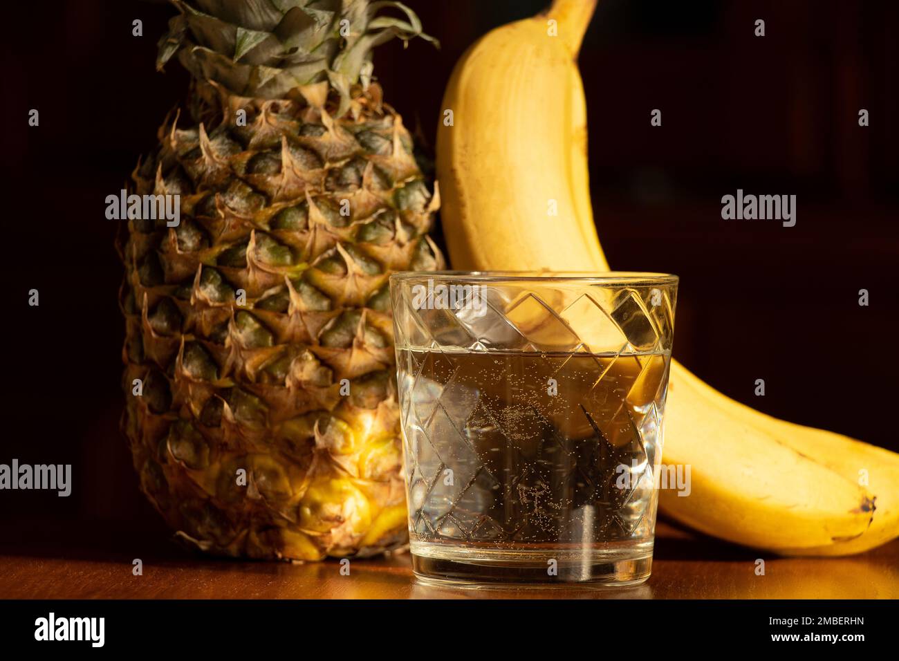 Pineapple and bananas lie next to a glass of water on a white background, vegan diet and food ...