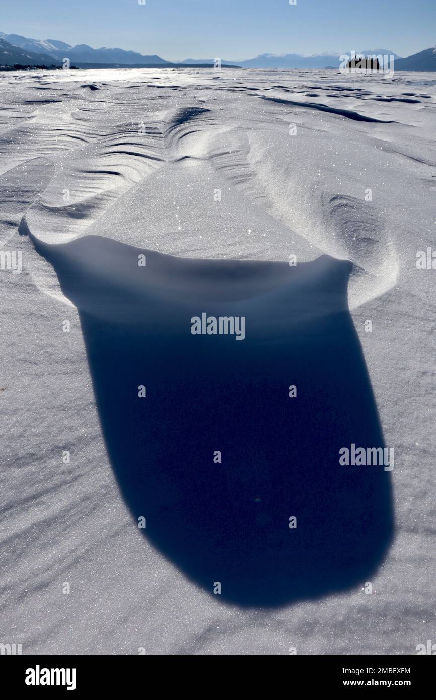 Textures and lines in blown sparkling snow on a frozen lake, with blue ...