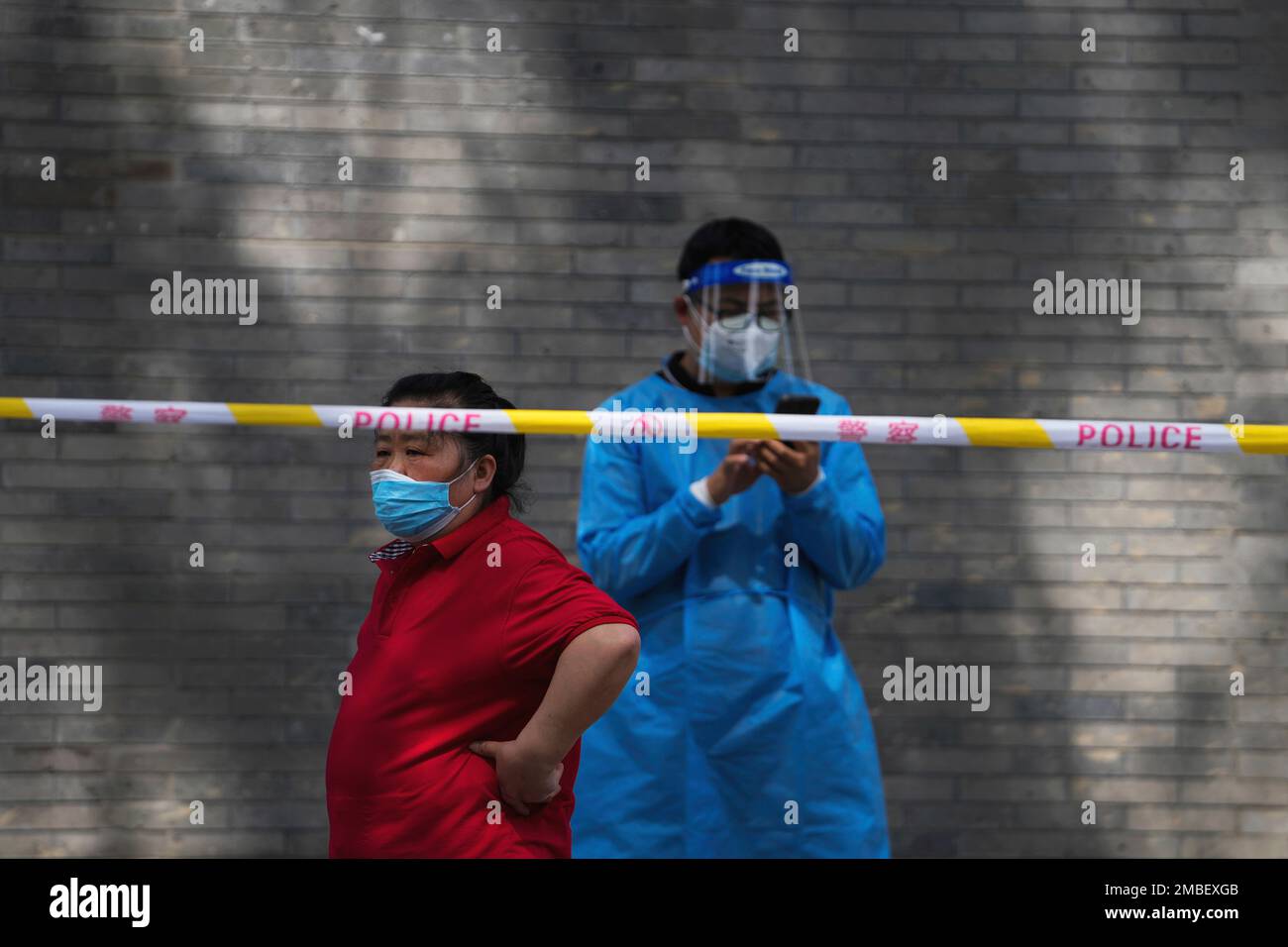 A worker in protective suit browses his mobile phone as a resident ...